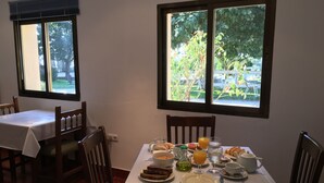 Uma sala de jantar com mesa posta para o café da manhã, incluindo pão, suco e uma chaleira.