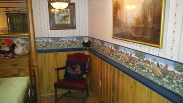 Um quarto com um banco de madeira, uma cadeira vermelha, uma cômoda de madeira, um quadro na parede e uma moldura decorativa na parte inferior da parede.