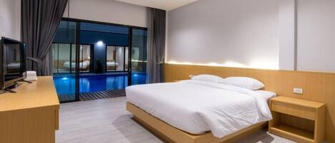 Quarto de hotel moderno com uma cama grande, uma mesa de trabalho e vista para uma piscina interior.