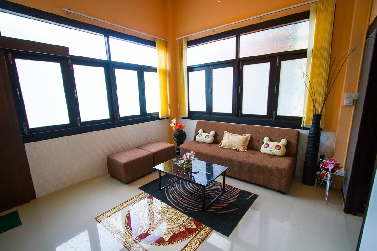 Uma sala de estar com um sofá, uma mesa de centro e uma janela grande com cortinas.