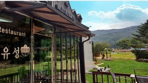 Um restaurante com vista para montanhas e um espaço gramado.