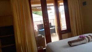 Quarto de hotel com uma cama, cortinas e vista para uma área de estar externa.