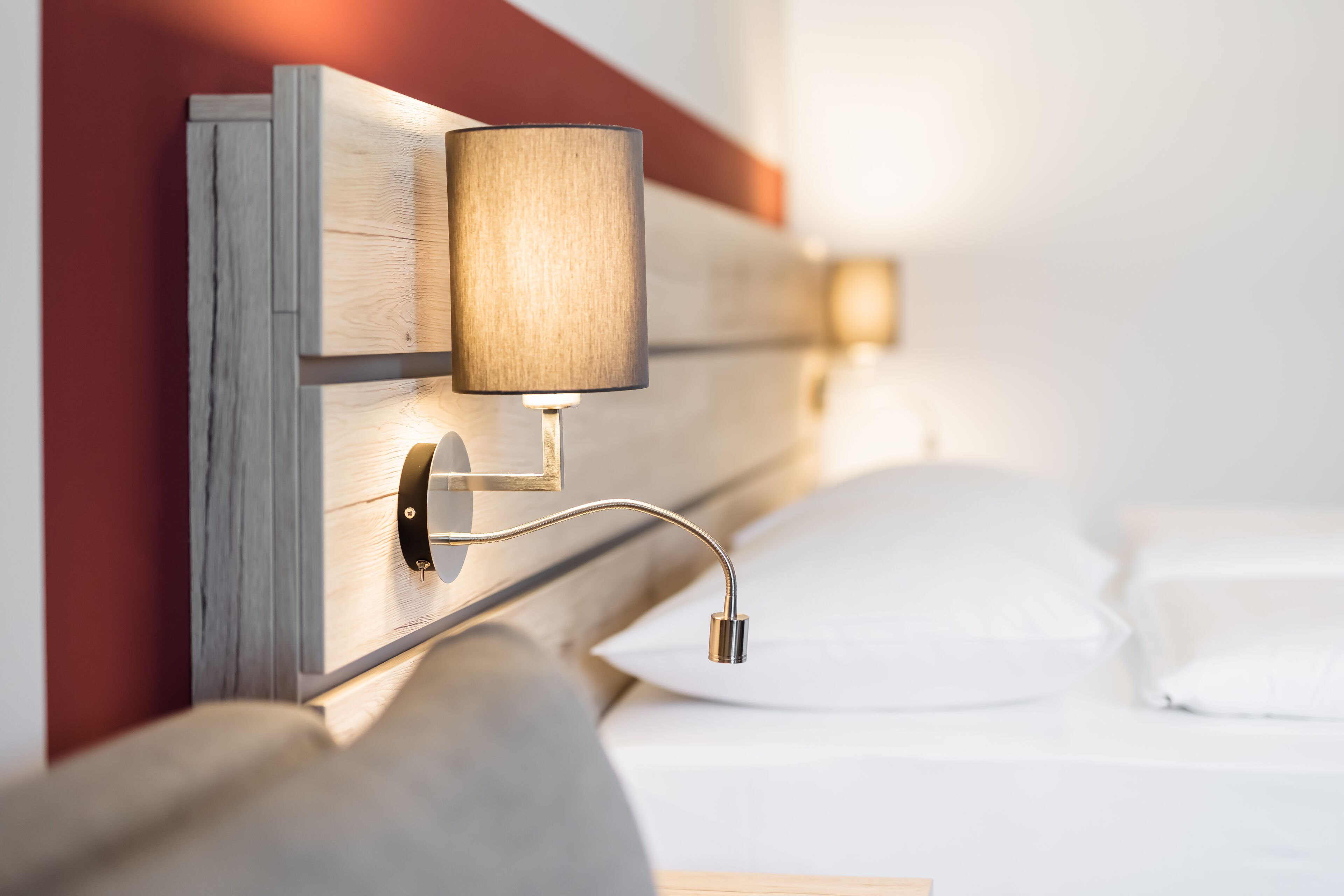Uma cama moderna com cabeceira de madeira e uma luminária fixada na parede.