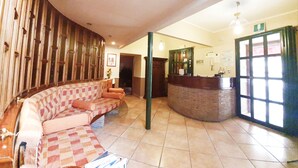 Um lobby com um sofá quadriculado, uma mesa de recepção e uma janela ampla.