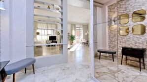 Um interior moderno com piso de mármore, sala de jantar com mesa e cadeiras, e área de estar com um banco.