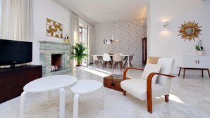 Uma sala de estar moderna com lareira, espaço de jantar e televisão.