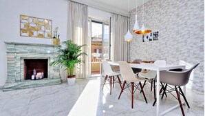 Uma sala de jantar moderna com lareira de mármore, mesa de jantar branca e cadeiras.