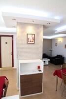 Uma sala de estar moderna com um painel de entretenimento branco, uma lareira e um espaço de refeições com toalha vermelha.