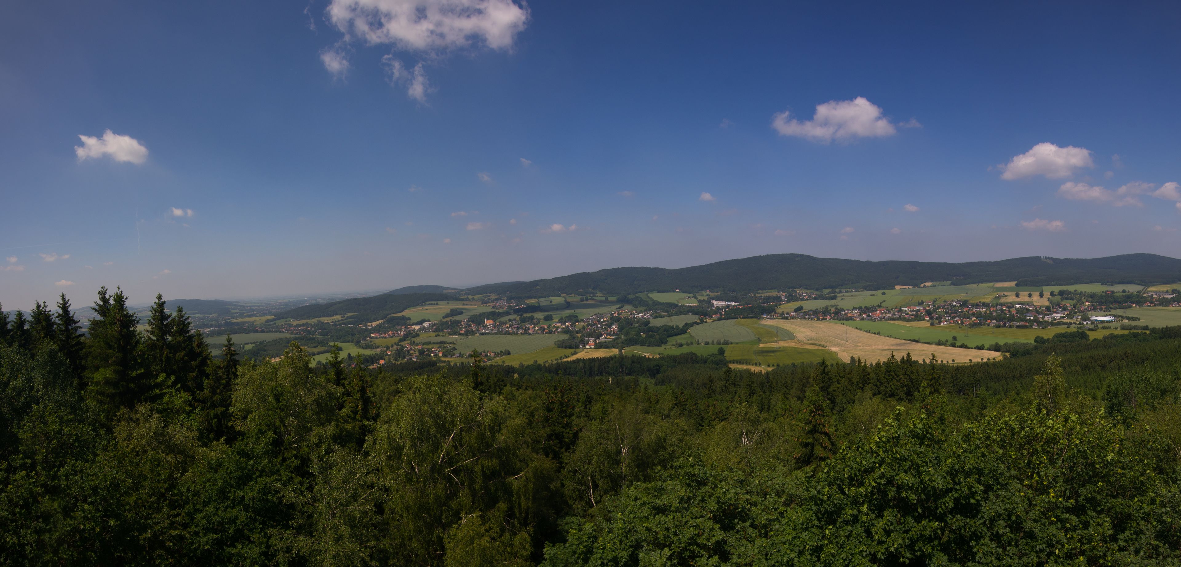Vista panorâmica de uma cidade aninhada num vale, com colinas ondulantes ao fundo.