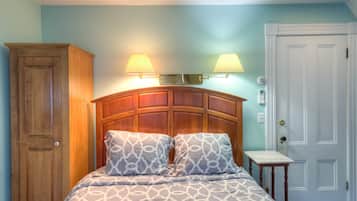 Quarto com cabeceira de madeira, duas luminárias de cabeceira, mesa de apoio e porta com chave de serviço.