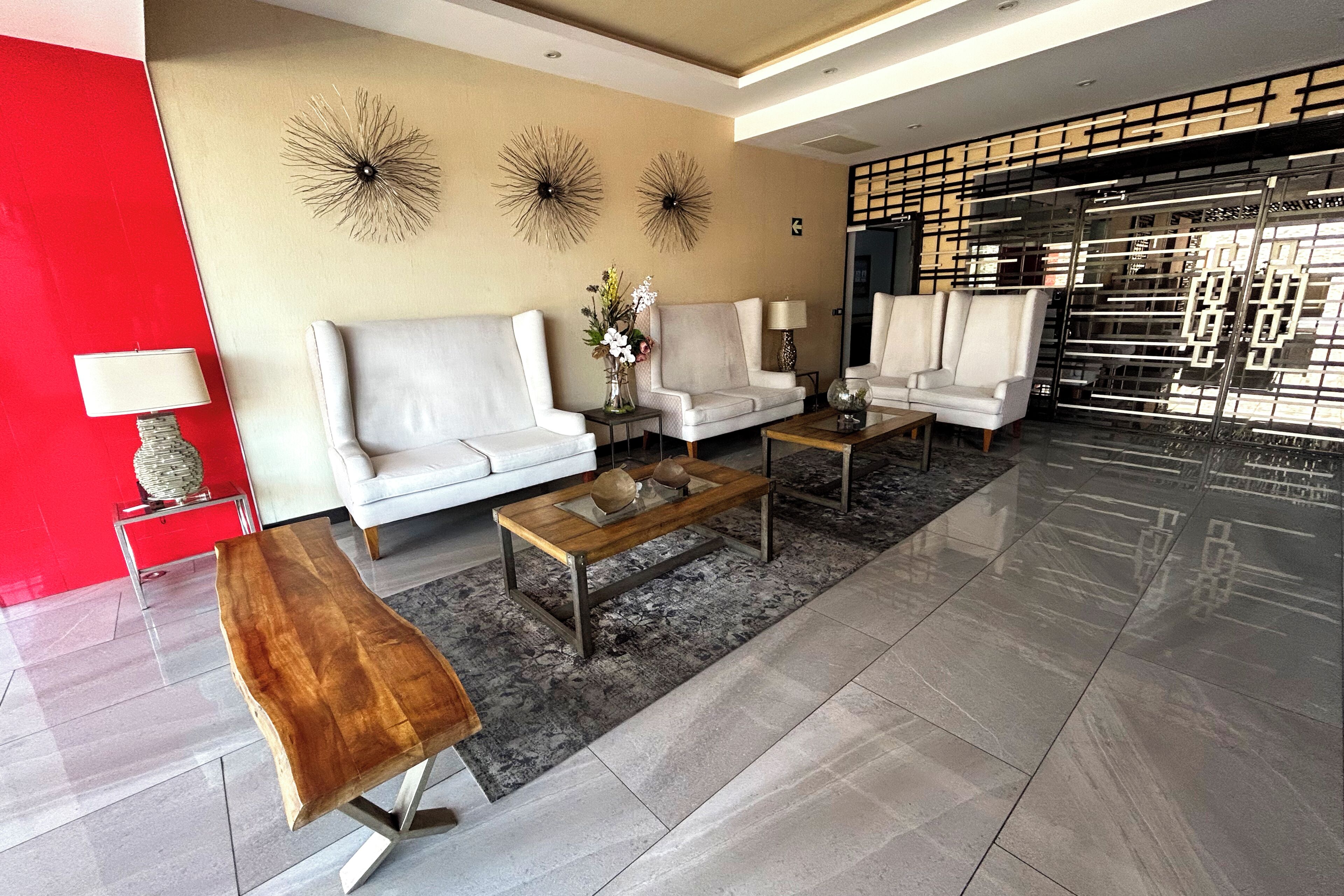 Uma sala de estar moderna com sofá, duas poltronas, uma mesa de centro e uma parede de destaque vermelha.