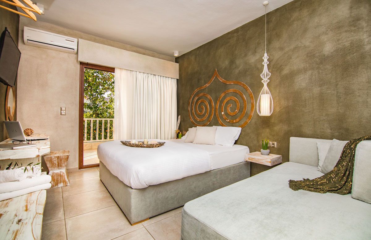 Quarto moderno com uma cama grande, uma cama menor, uma escrivaninha com um laptop, um banheiro com banheira e uma varanda com cortinas.