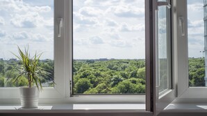 Uma janela com vista para uma paisagem verde e uma planta em vaso no parapeito.