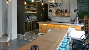 Uma área de bar moderna com balcão de madeira, luminárias pendentes e parede com padrão herringbone.