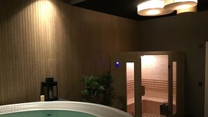 Uma área de spa com hidromassagem, parede de madeira e sauna.
