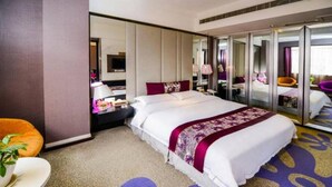 Quarto de hotel com uma cama grande, uma mesa de cabeceira, uma cadeira, um espelho e uma planta.