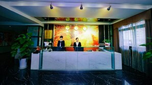 Uma área de recepção de hotel com um balcão de mármore, dois recepcionistas e uma grande pintura abstrata na parede.