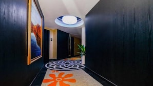Um corredor com piso estampado, luminária no teto e quadro na parede.