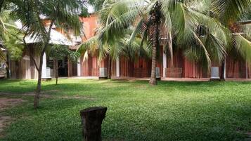 Um pátio com palmeiras e um edifício com paredes vermelhas e janelas com contraventanas brancas.