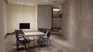 Uma sala de conferências moderna com uma mesa grande, cadeiras, uma TV de tela plana e um painel de vidro.