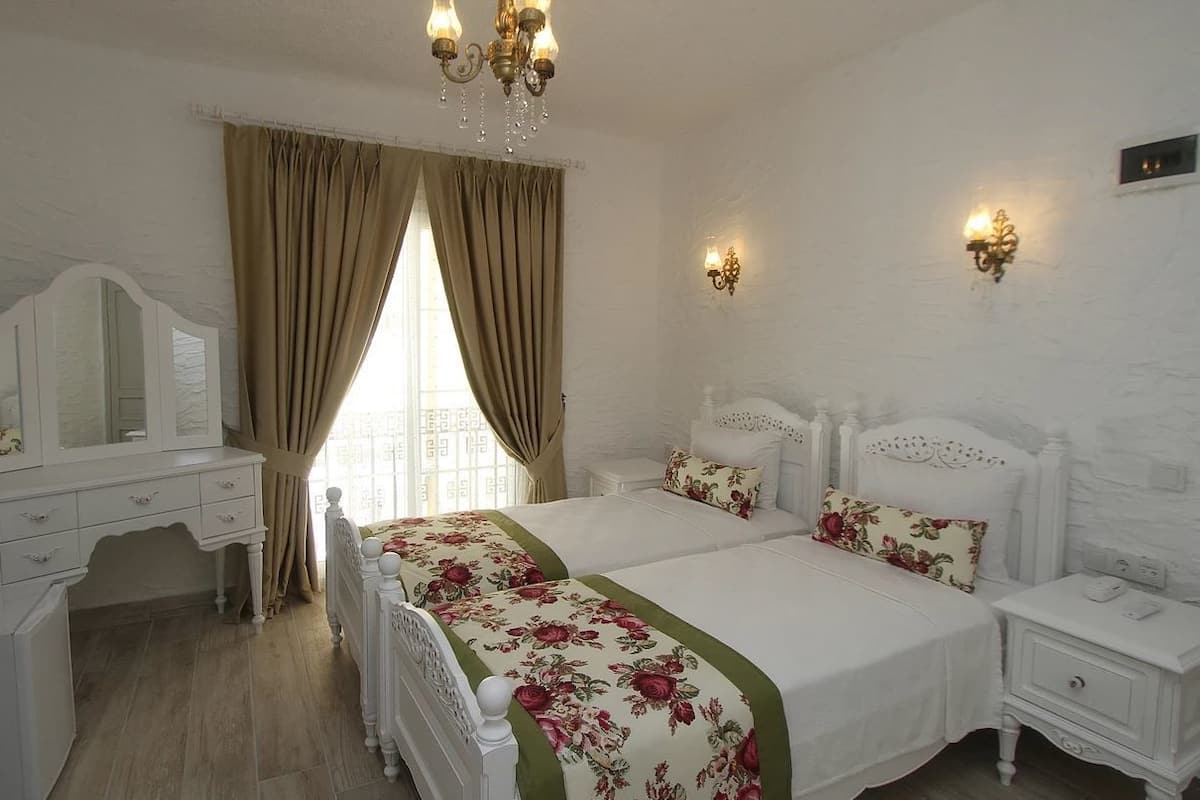 Quarto com uma cama grande, cômoda, espelho e duas mesas de cabeceira.