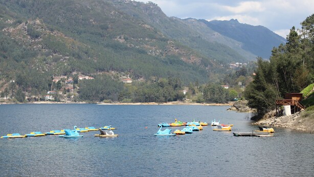 Um lago com barcos e montanhas ao fundo.