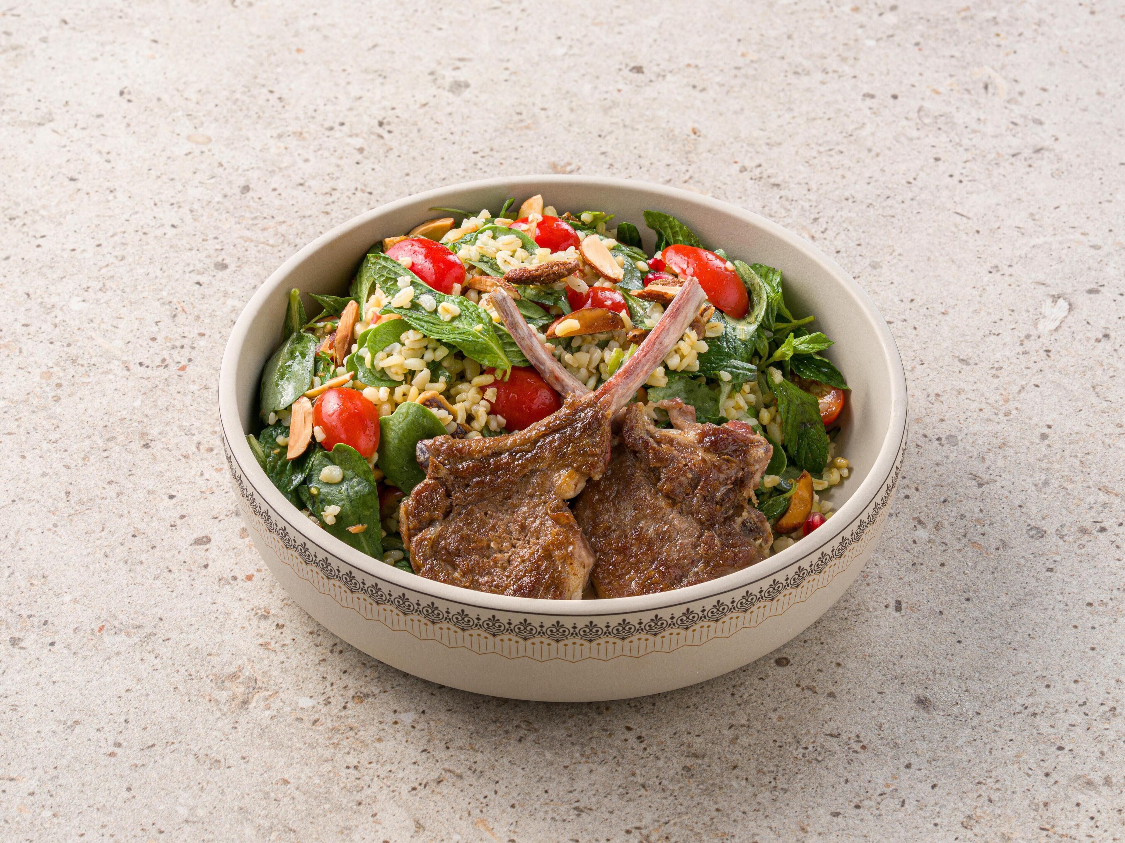 Uma tigela de comida com folhas verdes, tomates e carne.