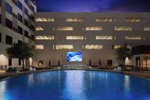 Piscina com um edifício moderno ao fundo.