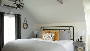 Uma cama bem arrumada com roupa de cama listrada, um travesseiro decorativo, uma mesa de cabeceira com abajur e um relógio fixado na parede.