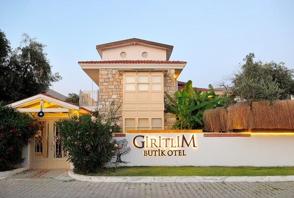 Giritim Butik Hotel com fachada de pedra, uma grande porta de garagem e um jardim bem cuidado.