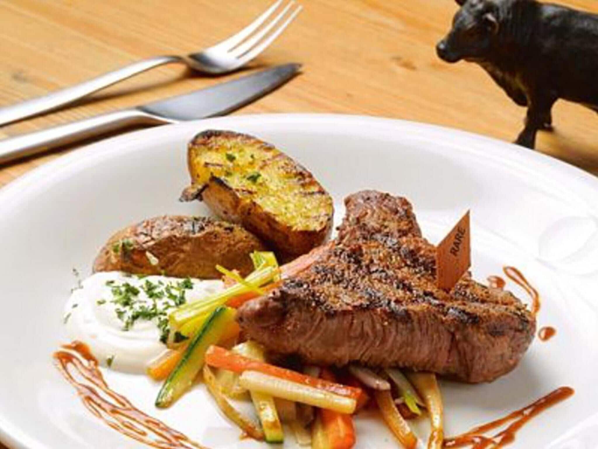 Prato com bife, batatas assadas e legumes.
