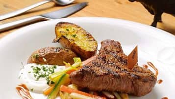 Prato com bife, batatas assadas e legumes.