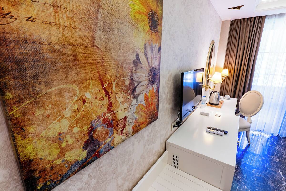 Uma casa de banho moderna com um grande quadro abstrato, uma cómoda com espelho e uma televisão.