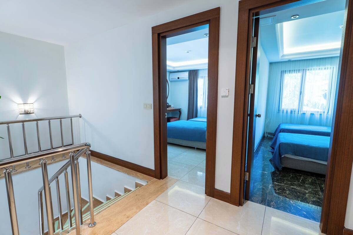 Quarto de hotel com cama, escrivaninha e janela com cortinas.