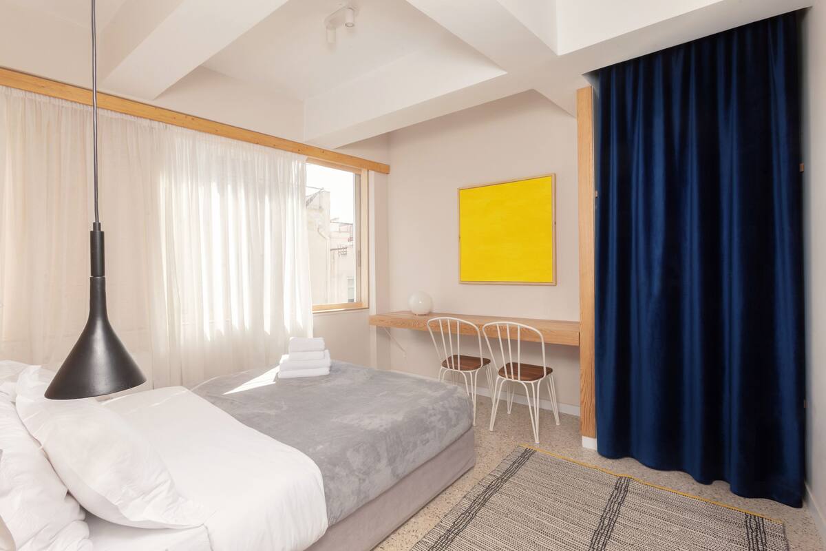 Quarto de hotel moderno com uma cama, uma escrivaninha e uma cadeira.