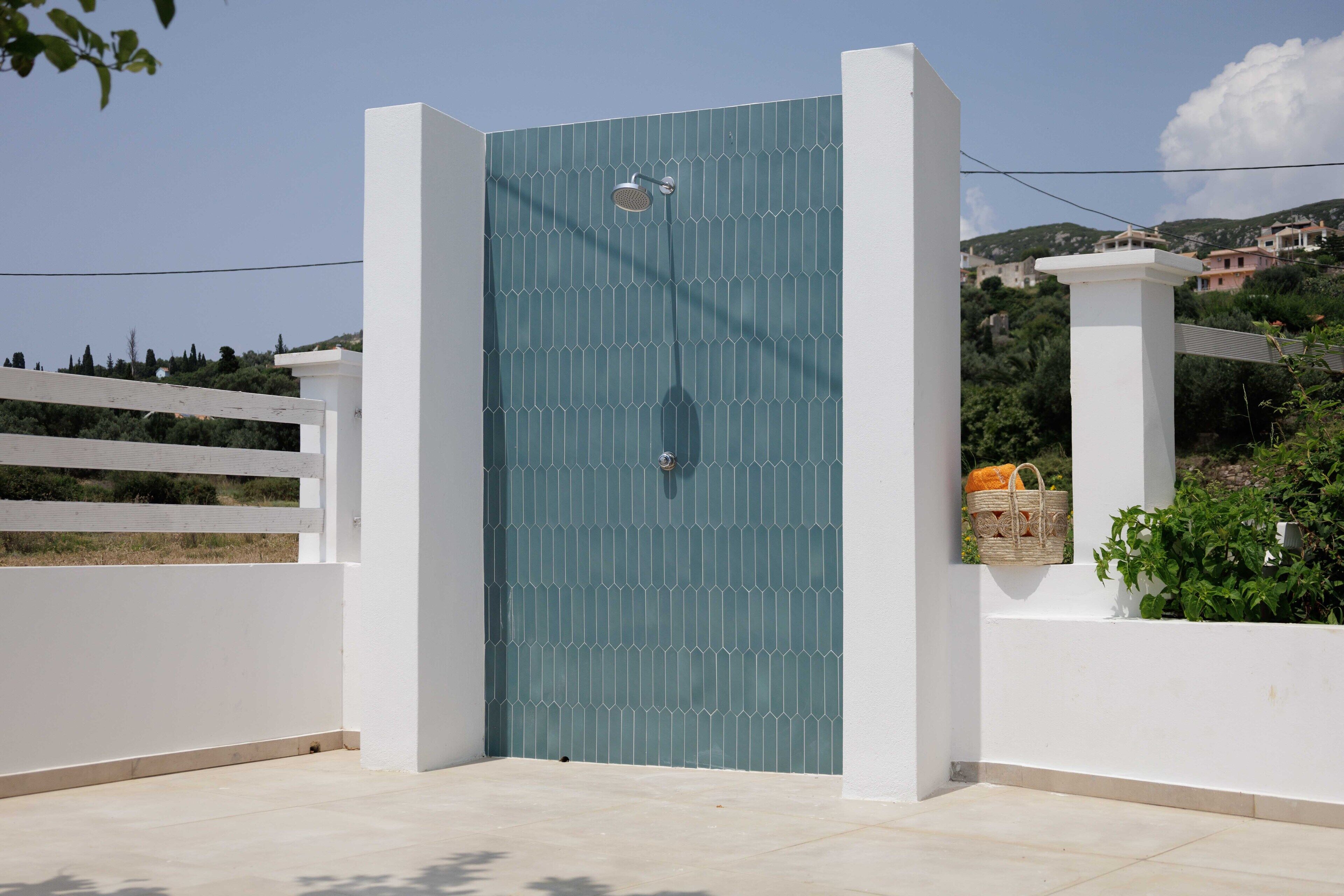 Um edifício moderno, com paredes brancas, porta azul-turquesa e uma pequena varanda com um cesto de vime.