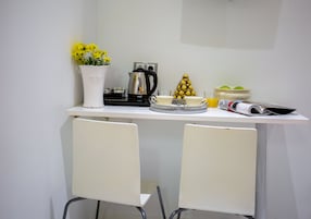 Uma cozinha compacta com cafeteira, uma pequena árvore de Natal e uma fruteira.