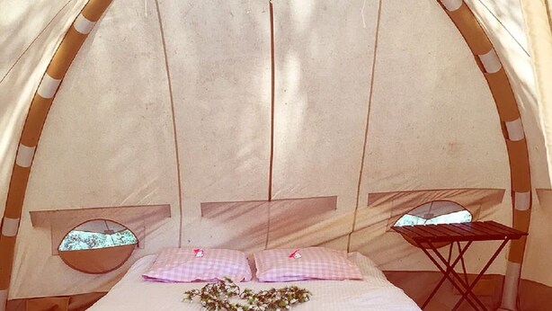 Uma tenda com uma cama, uma mesa pequena e uma janela.