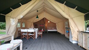 Uma tenda com área de jantar, cama e cozinha compacta.