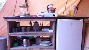 Uma cozinha com geladeira branca, prateleiras de madeira e diversos utensílios e recipientes.