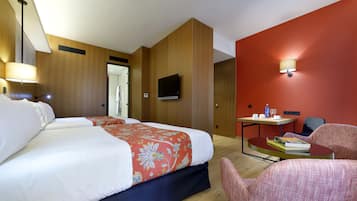 Quarto de hotel com uma cama grande, uma escrivaninha com cadeira, televisão e uma parede de destaque vermelha.