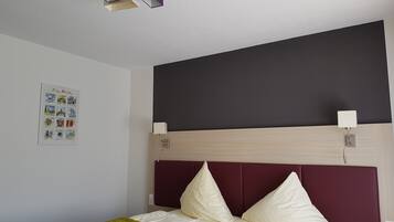 Quarto de hotel com cama, cabeceira, luminária na parede e um pôster.