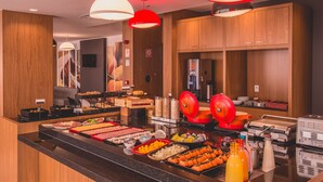 Buffet com diversos alimentos e uma máquina de café.