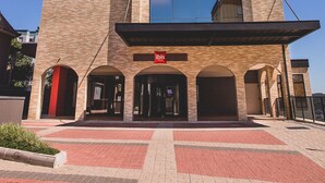 Um hotel com uma entrada em arco marcante, fachada de vidro ampla e um letreiro vermelho 'ibis'.