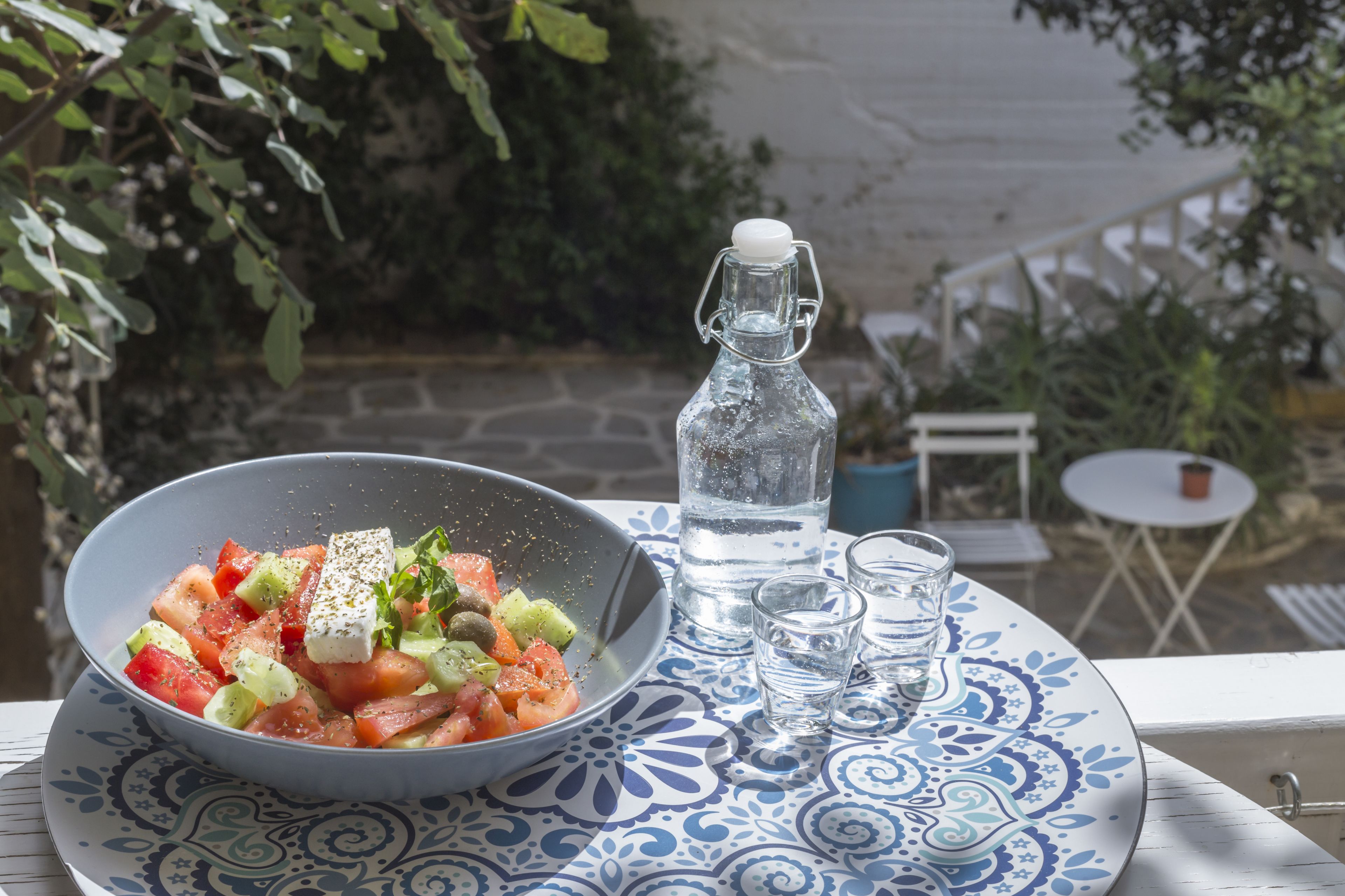 Uma mesa com uma saladeira, uma garrafa de água e dois copos.
