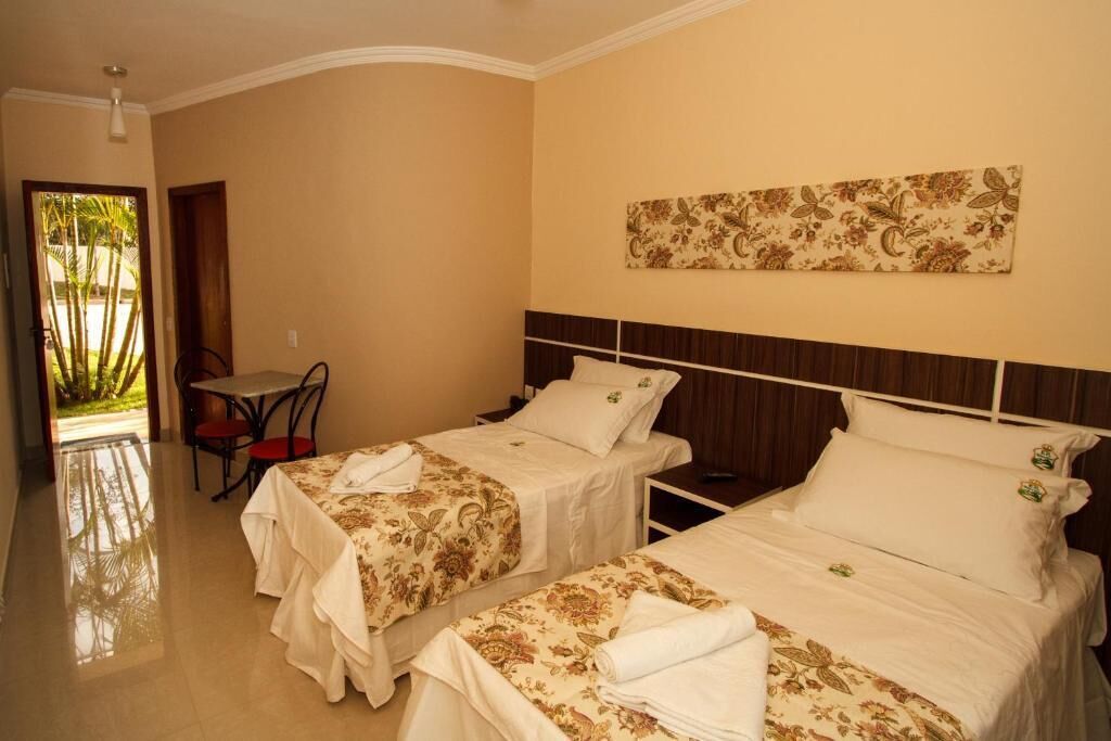 Quarto de hotel com duas camas, uma mesa de jantar e uma cadeira.