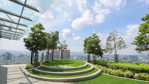 Jardim no terraço com paisagismo e vista para o horizonte da cidade.