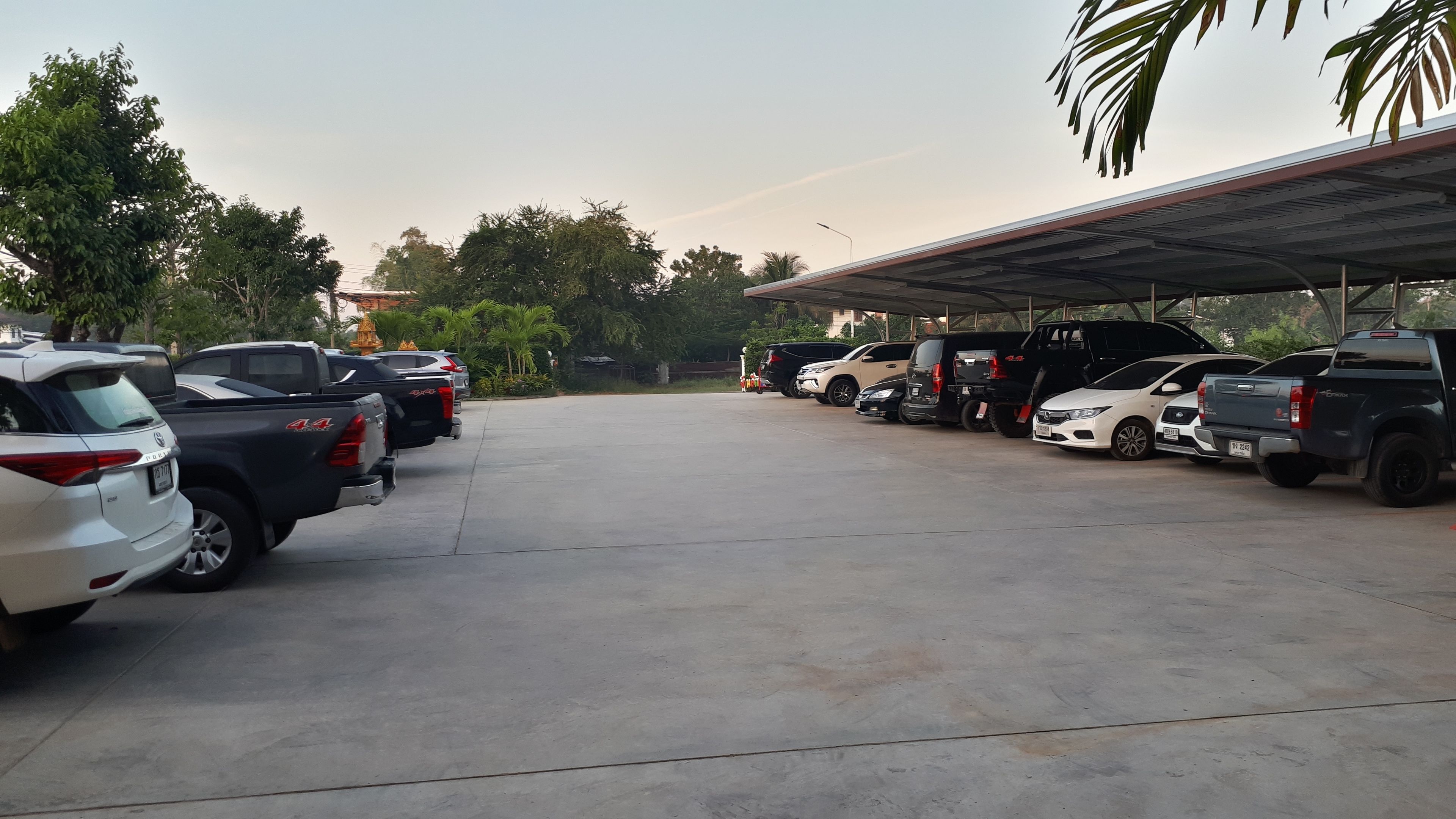 Uma área de estacionamento com diversos veículos, incluindo SUVs e caminhões, sob uma cobertura.