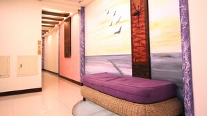 Um corredor com um banco roxo, uma parede com pintura de pássaros e iluminação embutida no teto.