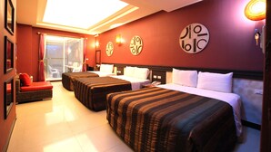 Quarto de hotel com três camas, um sofá e uma janela grande.